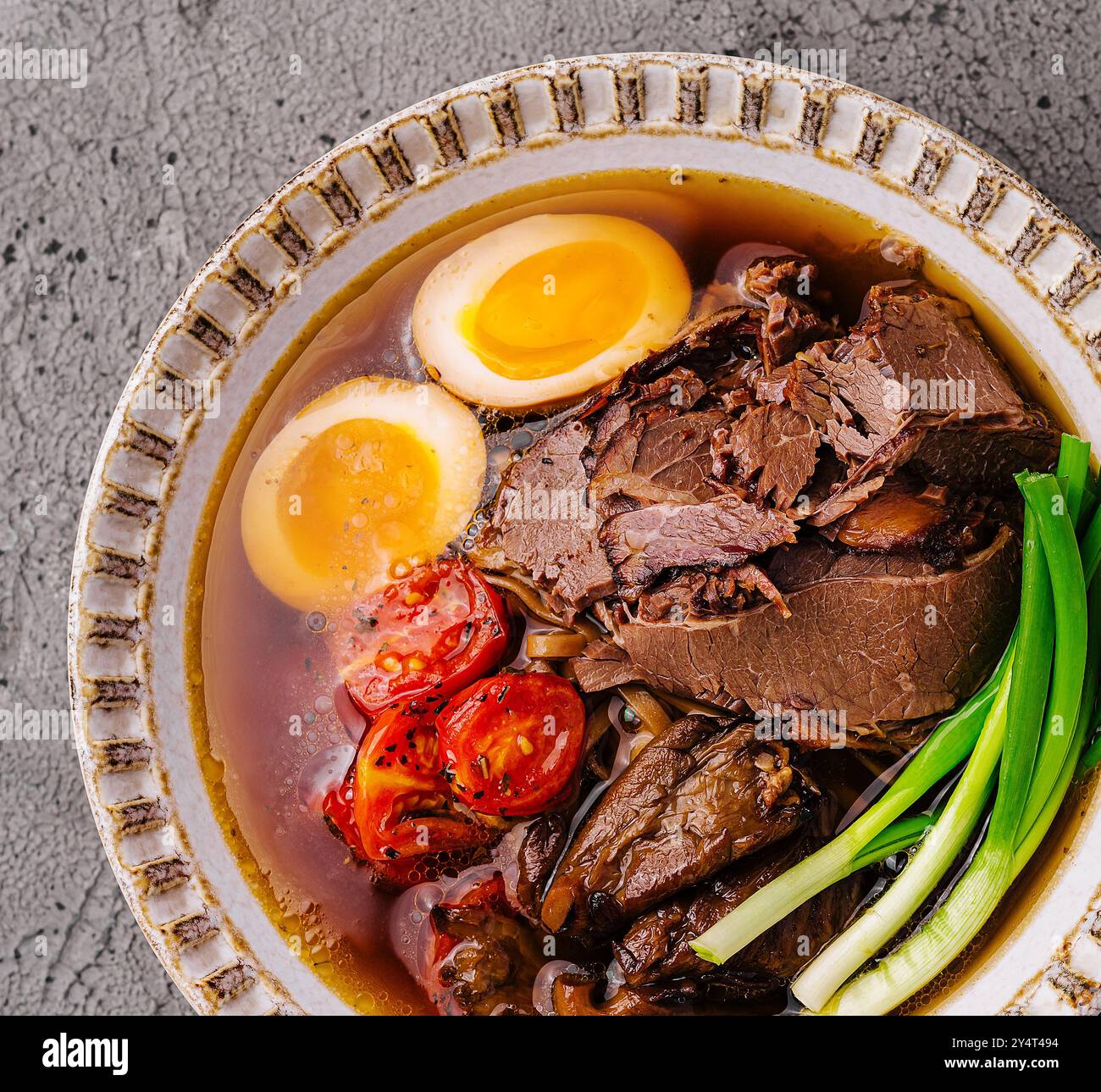 Traditional beef ramen with soft-boiled egg, tomatoes, and green onions ...
