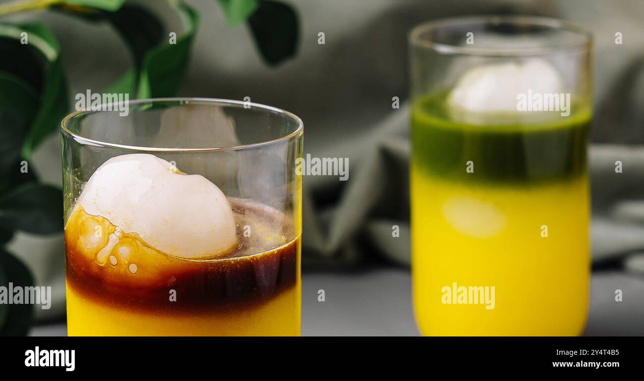 Elegant glasses with layered tropical cocktails and ice sphere Stock ...