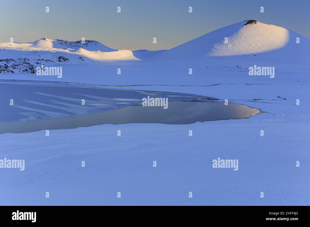 Morning light on a snowy lava field, lake, volcanic crater, snow ...