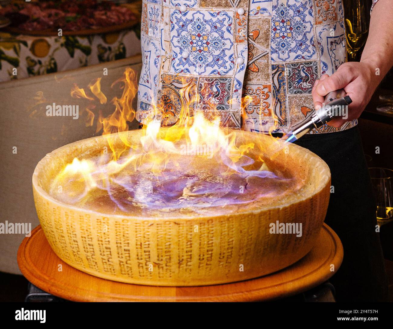 Chef preparing pasta in a flaming cheese wheel at a gourmet restaurant ...