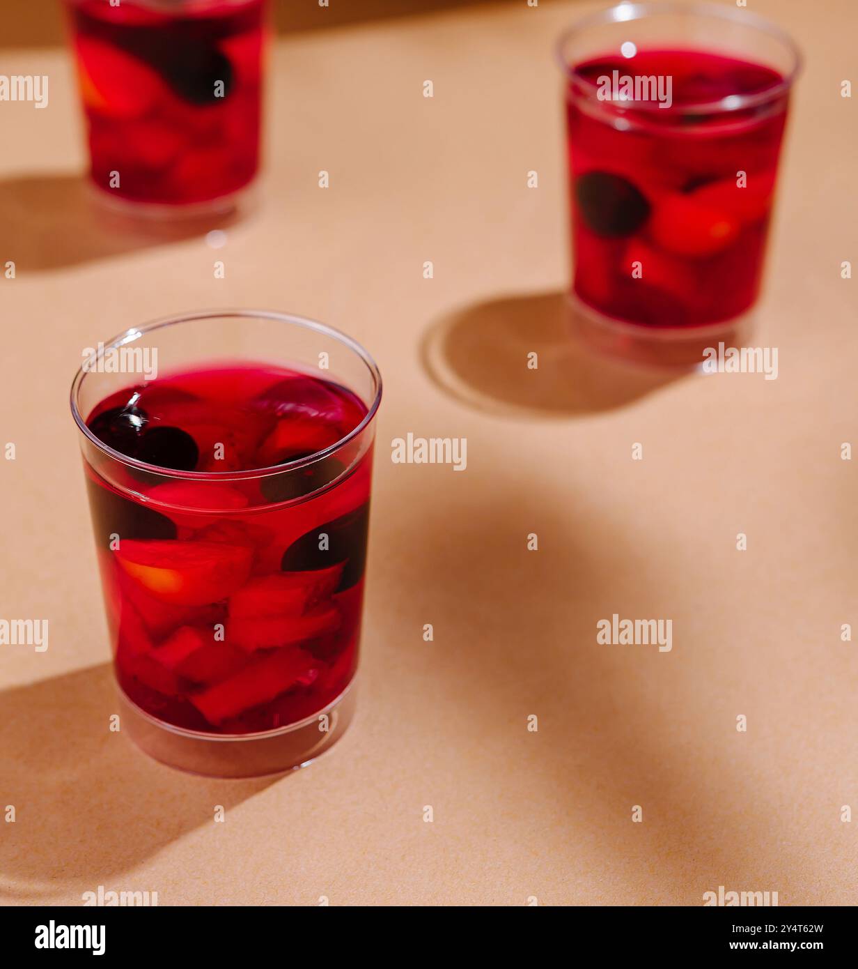 Three glasses of red berry mocktails on a warm beige background with ...