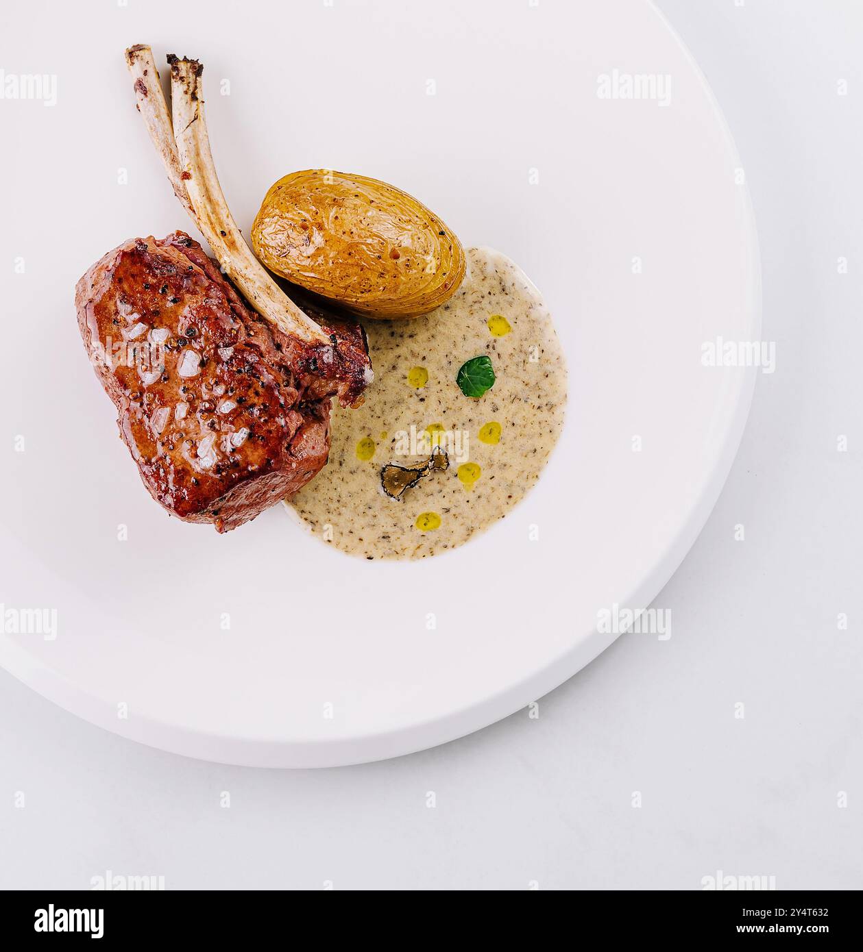 Elegant plating of a juicy lamb chop with golden roasted potatoes on a ...