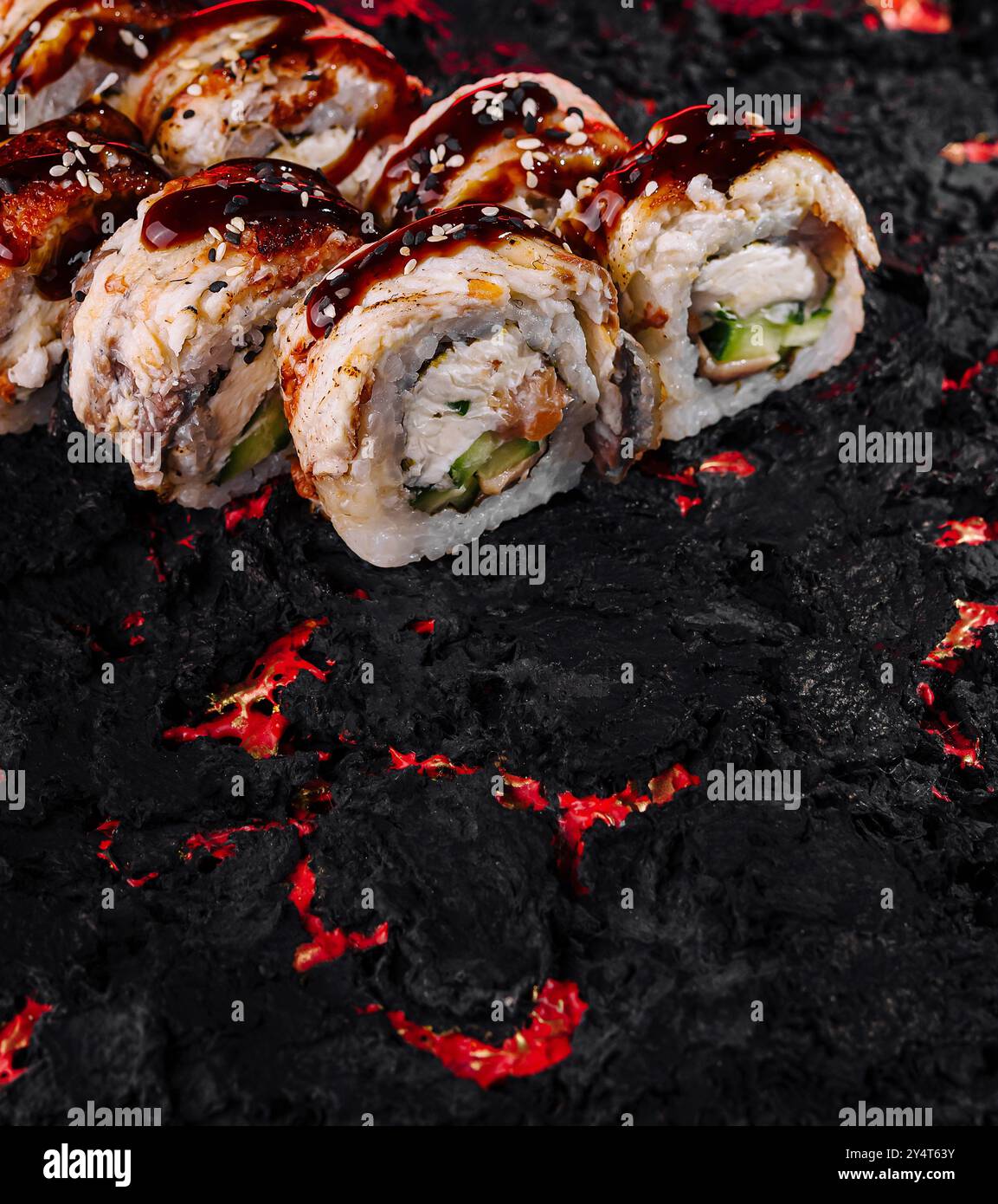 Creative sushi roll presentation on a fiery lava-like textured surface ...