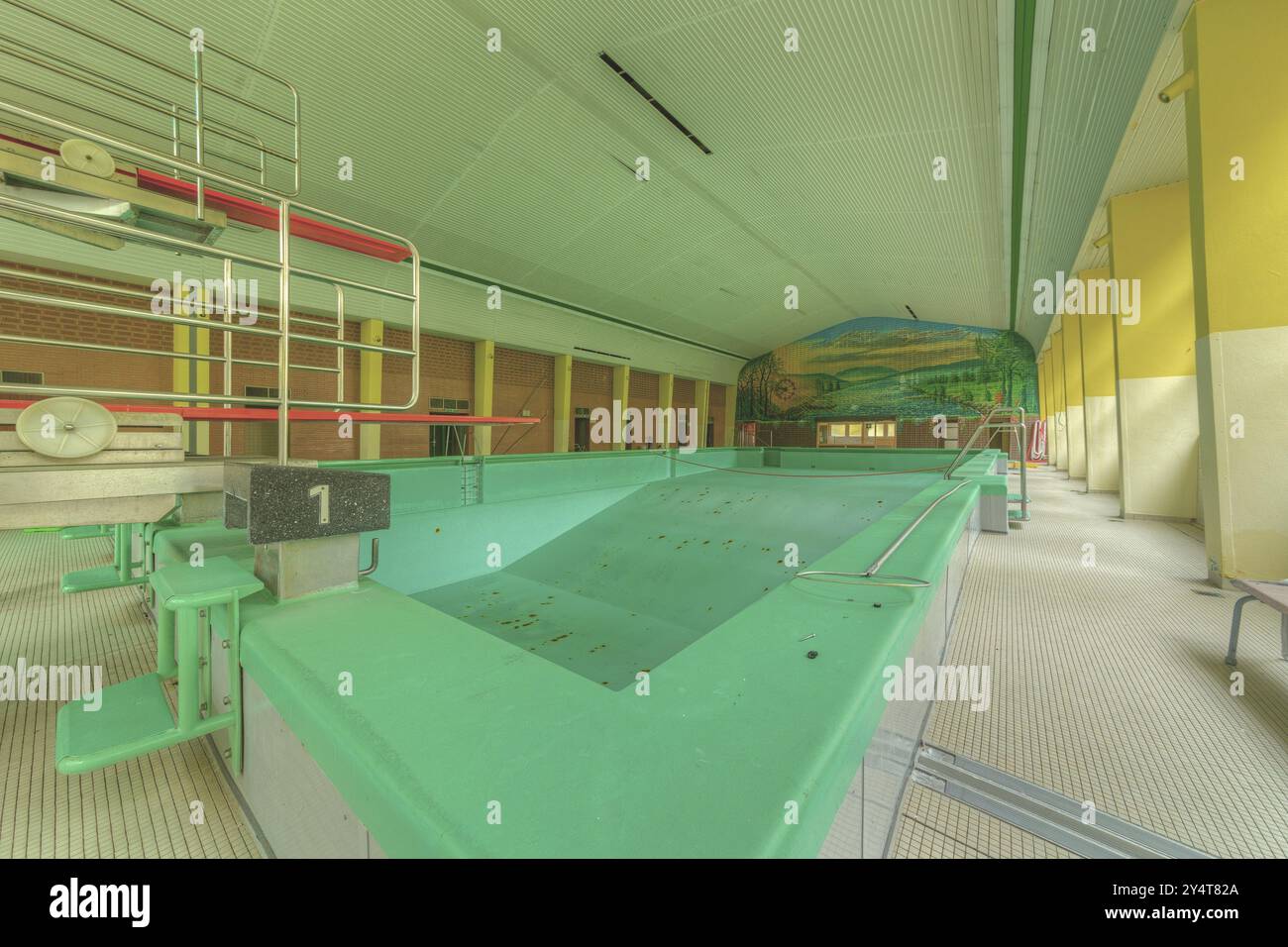 An empty indoor swimming pool with diving platform and railings ...