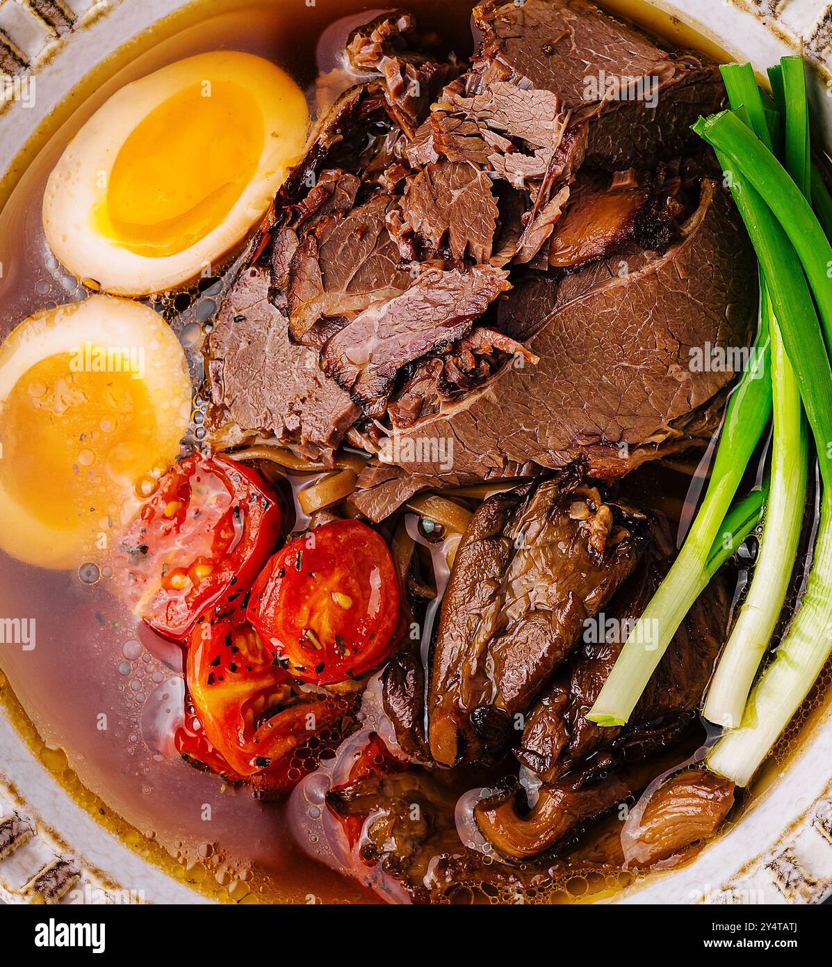 Traditional beef ramen with soft-boiled egg, tomatoes, and green onions ...