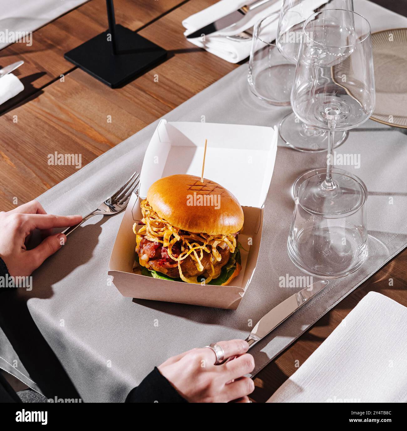 A person enjoys a delicious burger served in a stylish restaurant ...