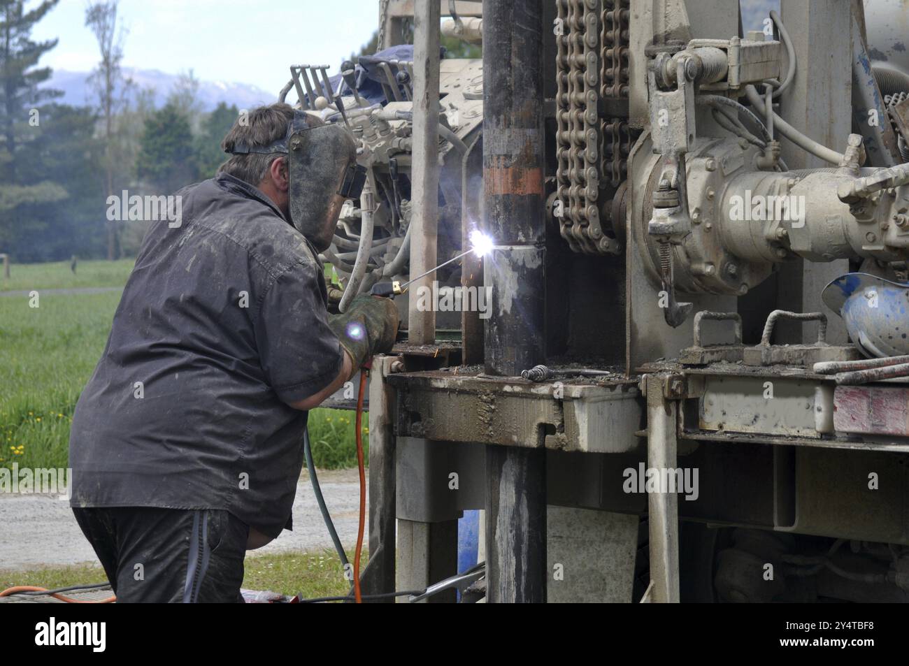 A drilling rig operator welds the casing for an underground water ...