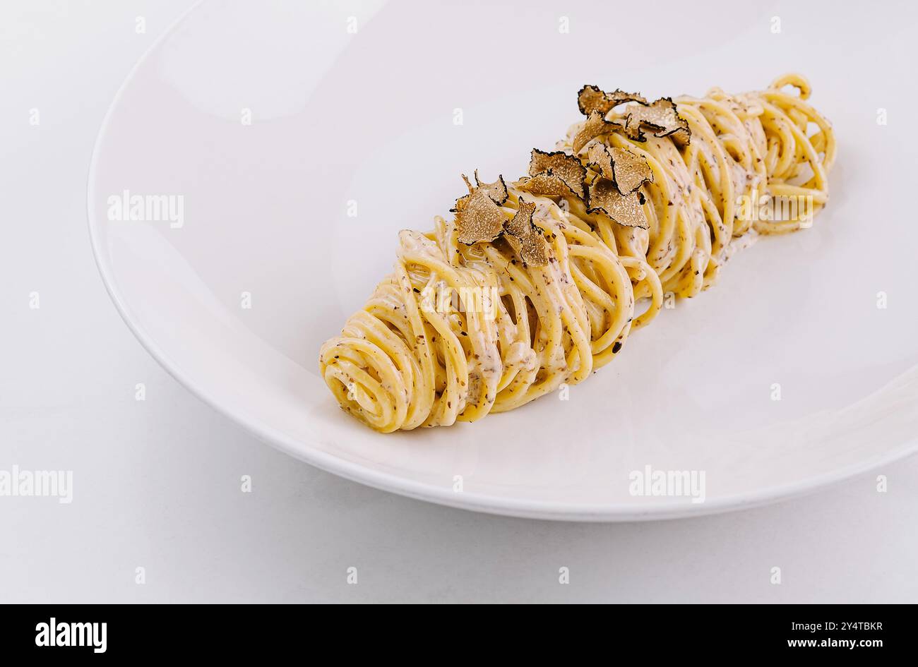 Elegant serving of spaghetti topped with shaved truffles on a sleek ...