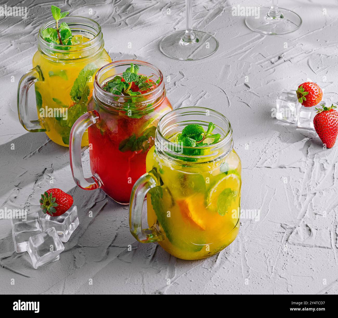 Colorful summer drinks with fruits and ice served on a textured table ...