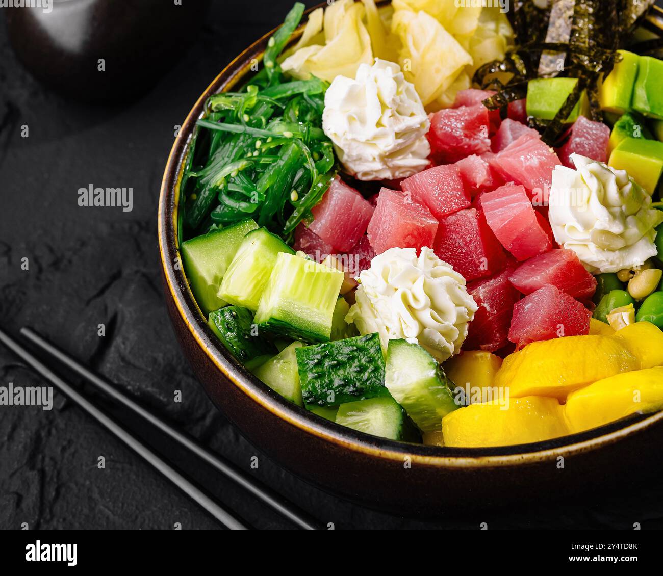 Colorful poke bowl featuring raw tuna, avocado, mango, and mixed ...