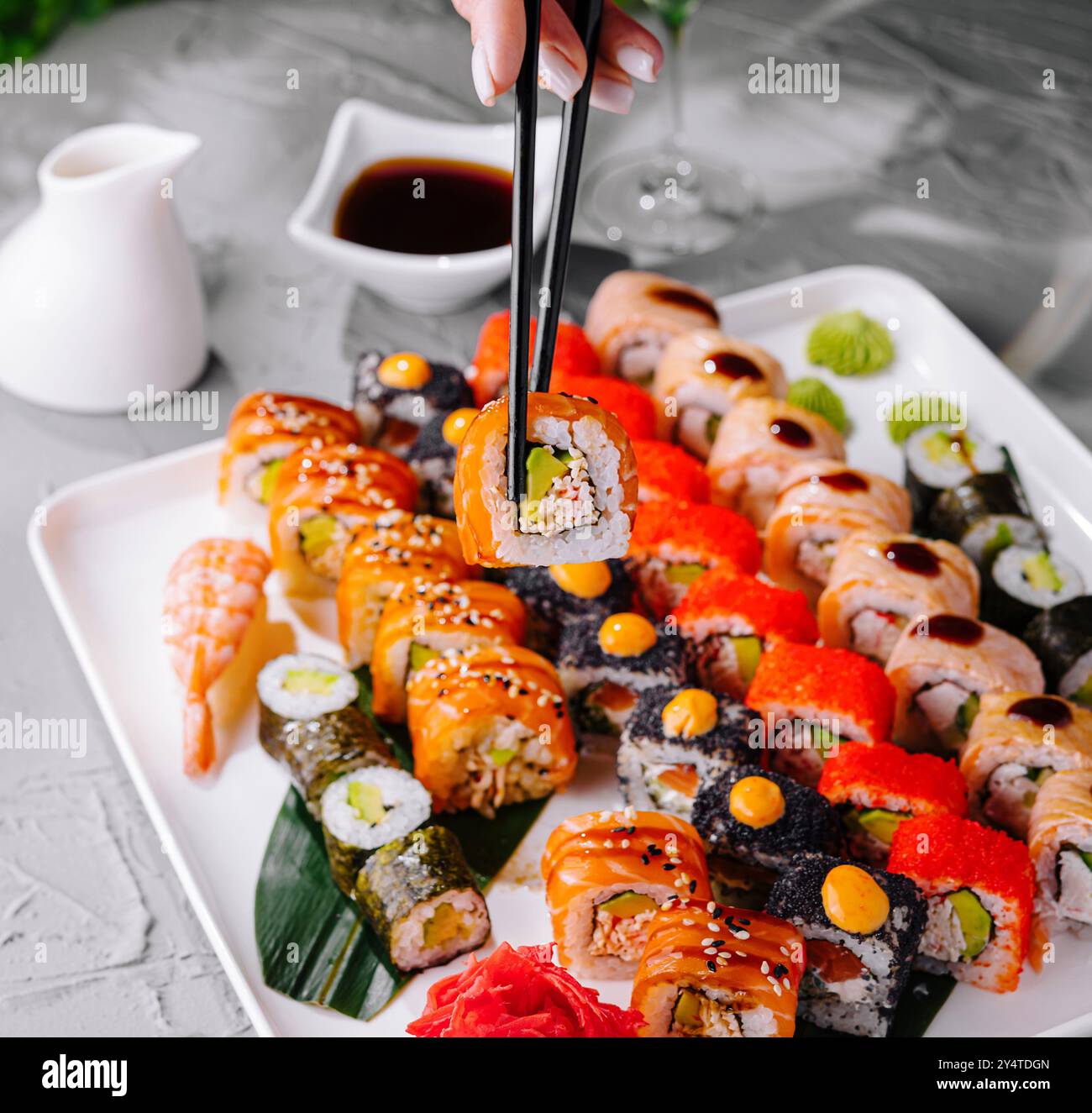 Close-up of a person using chopsticks to pick a sushi roll from an ...