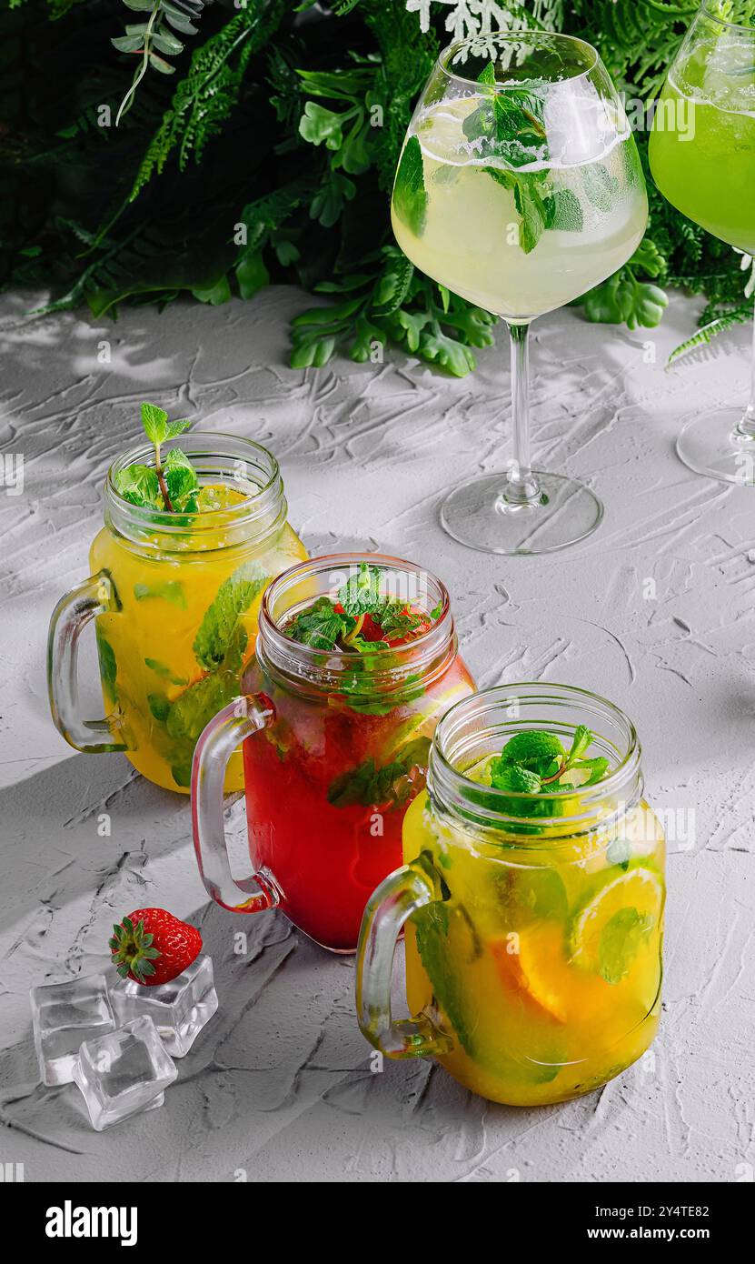 Colorful summer drinks with fruits and ice served on a textured table ...