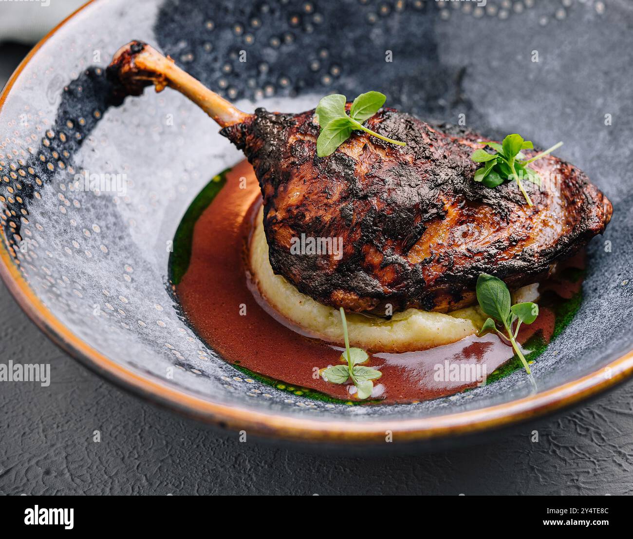 Exquisite duck confit served on creamy puree with a modern dark ceramic ...