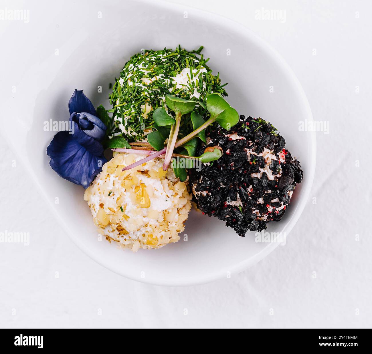 Trio of cheese balls coated with various herbs served on a stylish dish ...