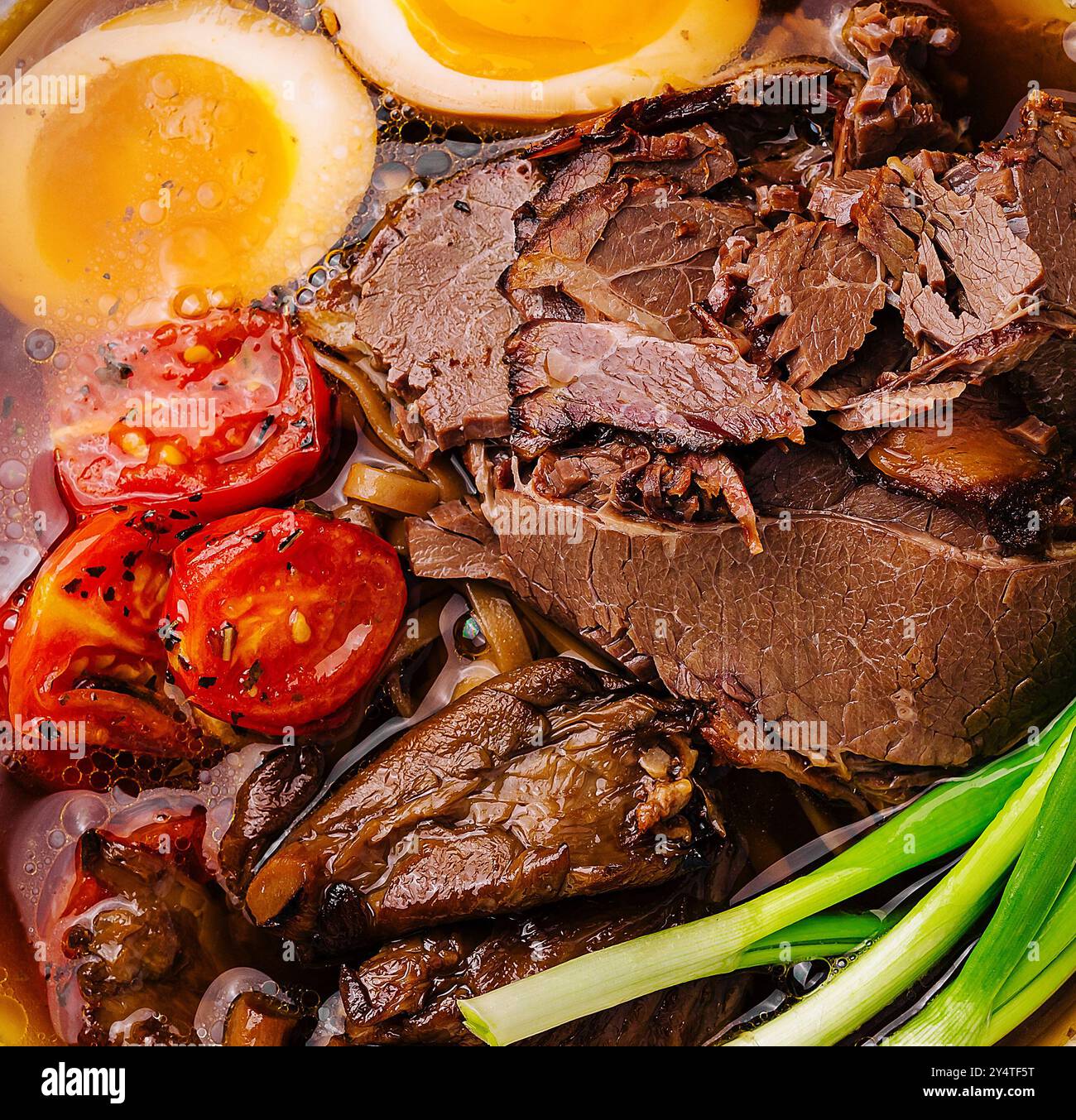 Traditional beef ramen with soft-boiled egg, tomatoes, and green onions ...