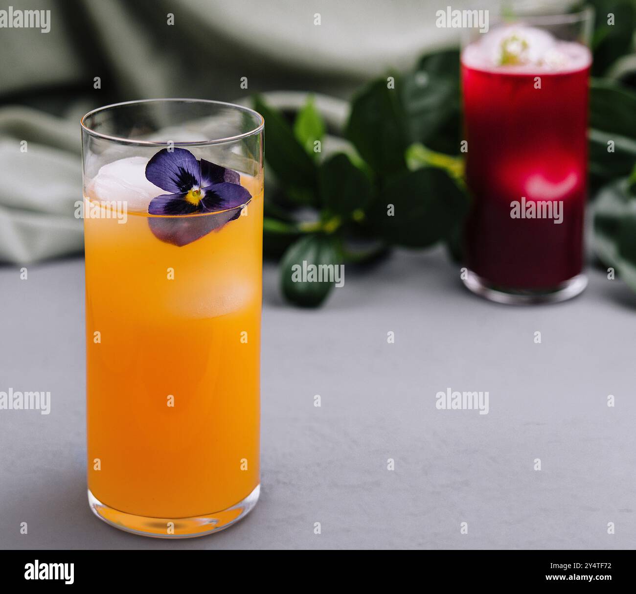 Chic glass of orange cocktail adorned with a pansy on a sophisticated ...