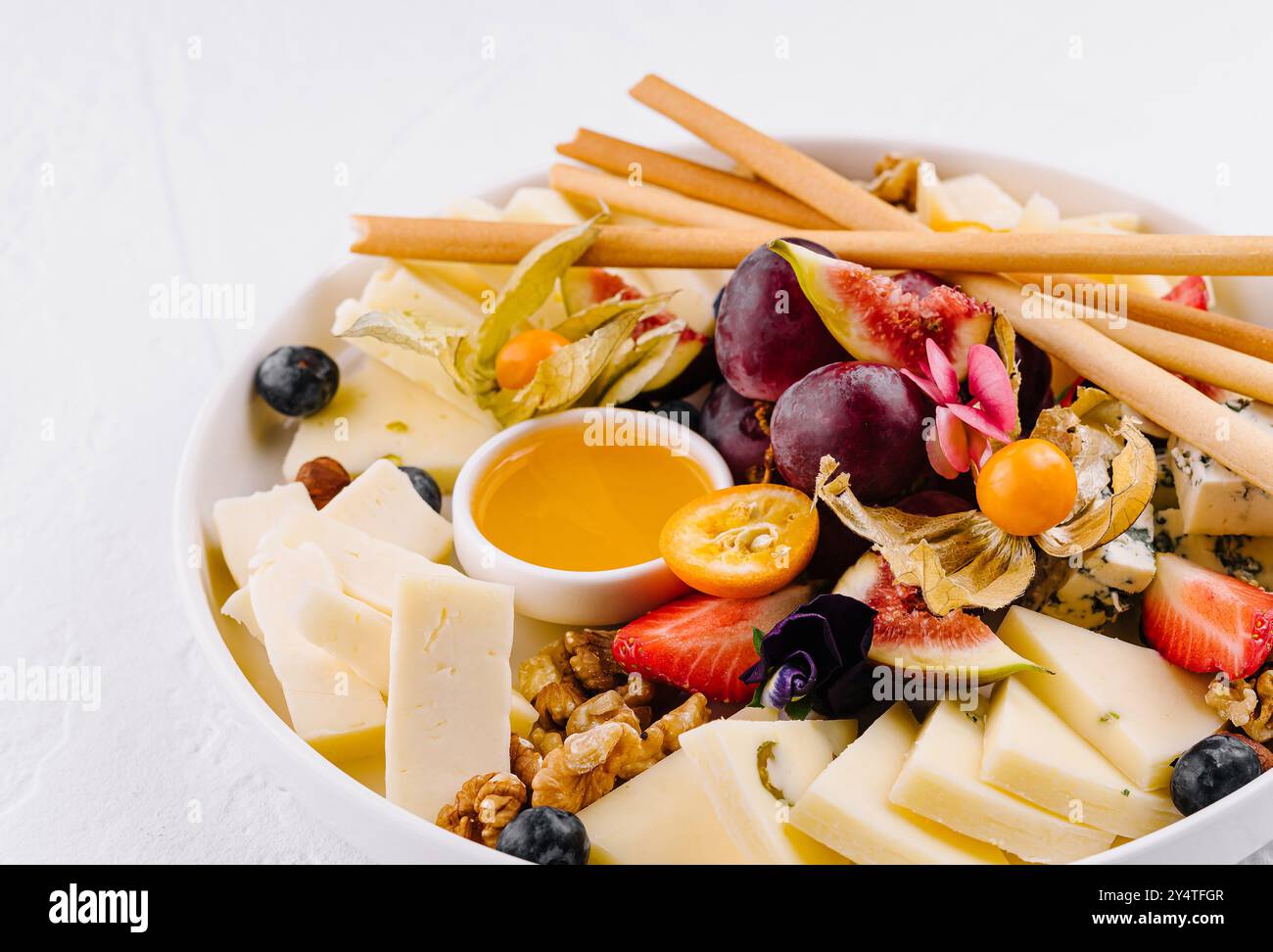 Elegant cheese board with assorted cheeses, fruits, nuts, and honey ...