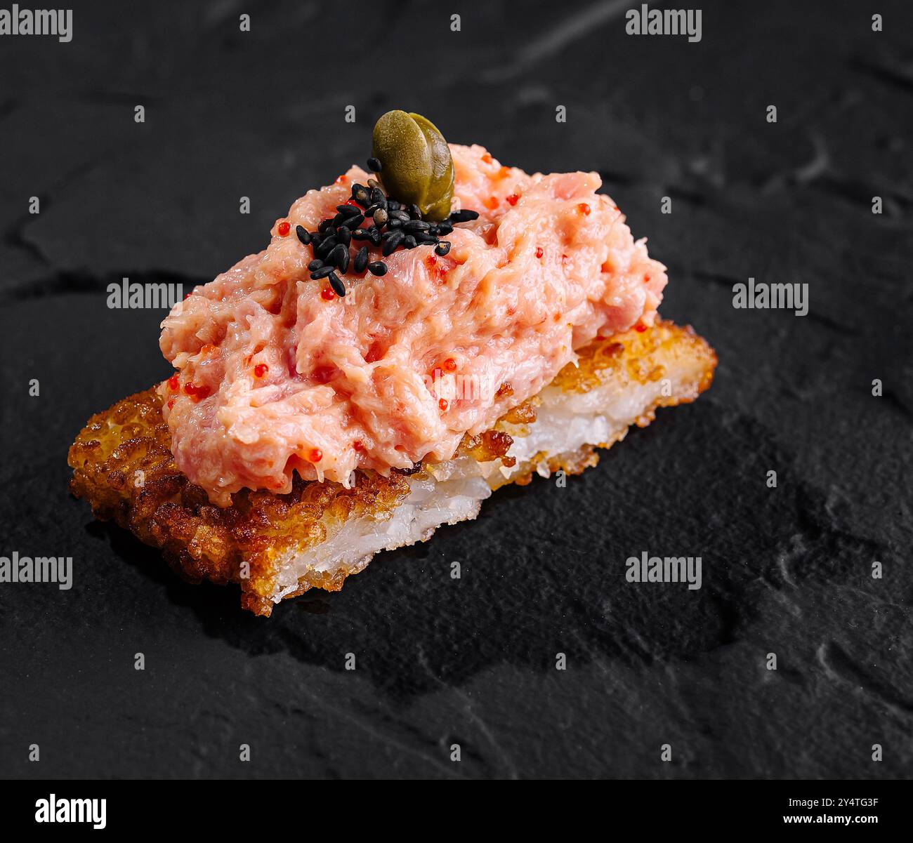 Elegant salmon tartare on a crispy rice base, garnished with capers ...