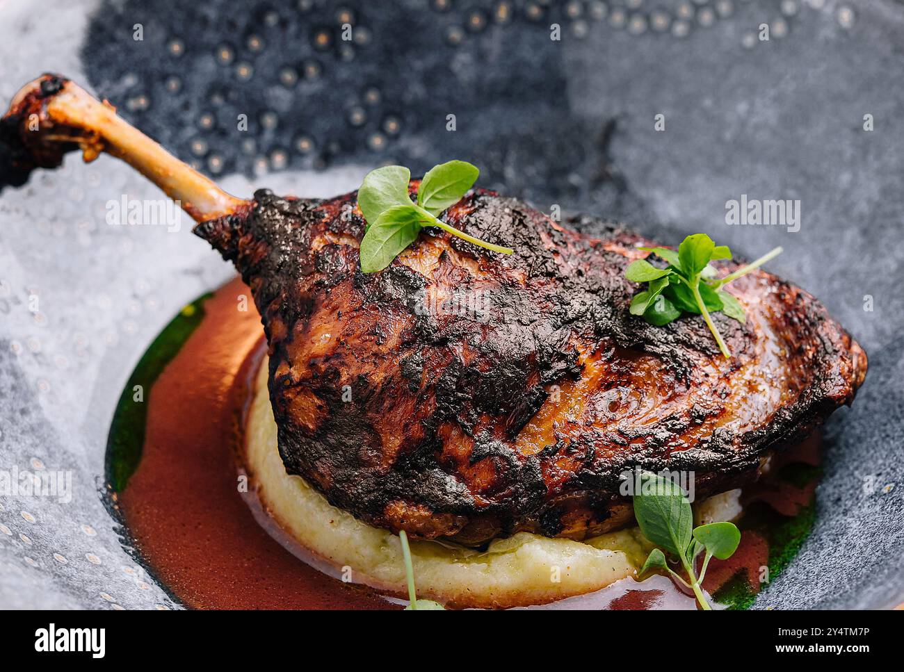 Succulent roasted duck leg served on a bed of puree with herb garnish ...