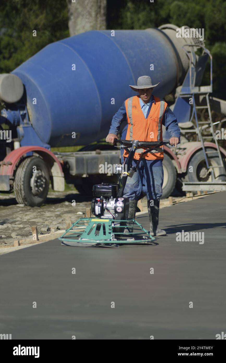 A builder uses a mechanical float to finish a slab of concrete at a ...