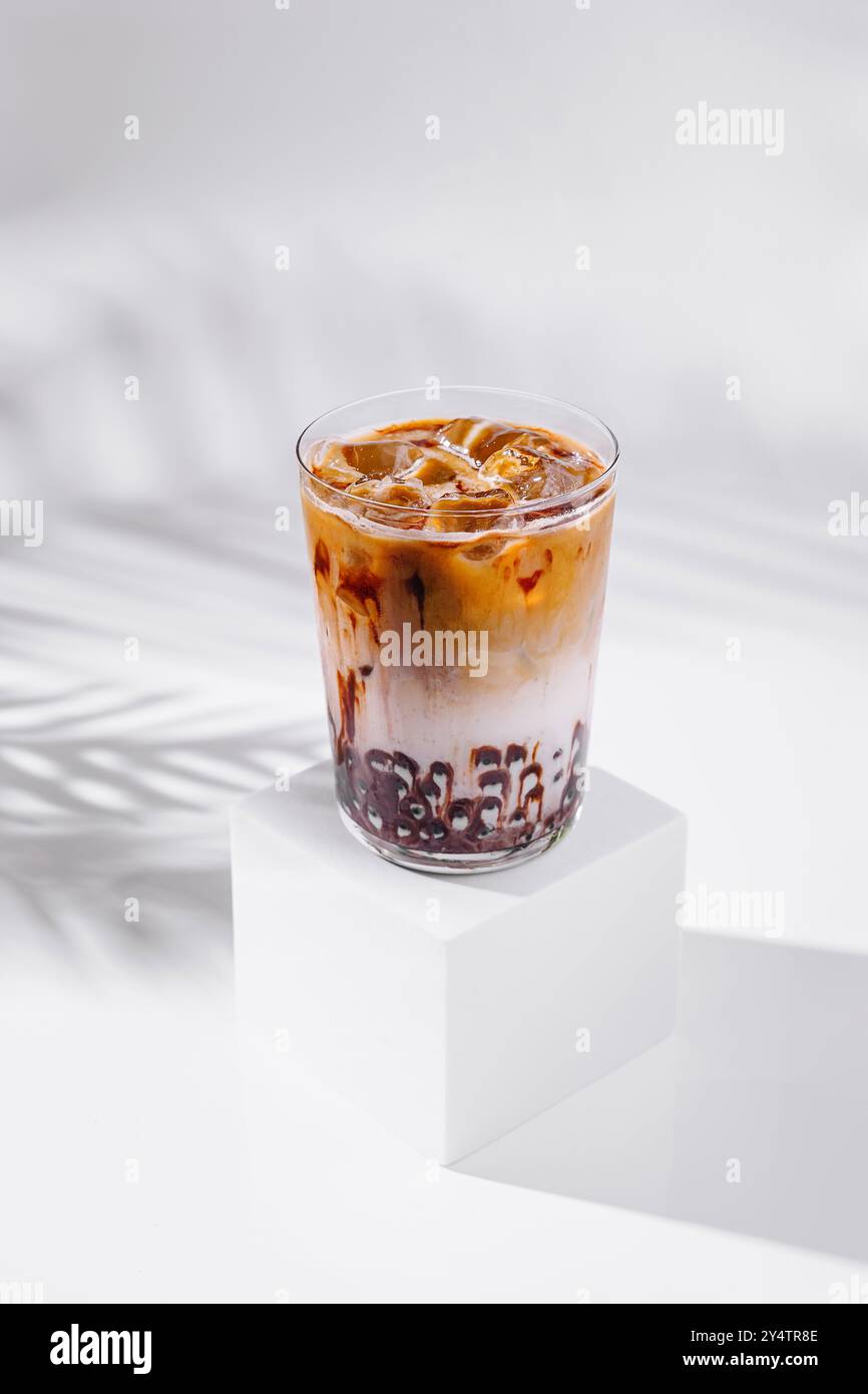 Refreshing iced coffee latte with chocolate syrup is standing on white ...