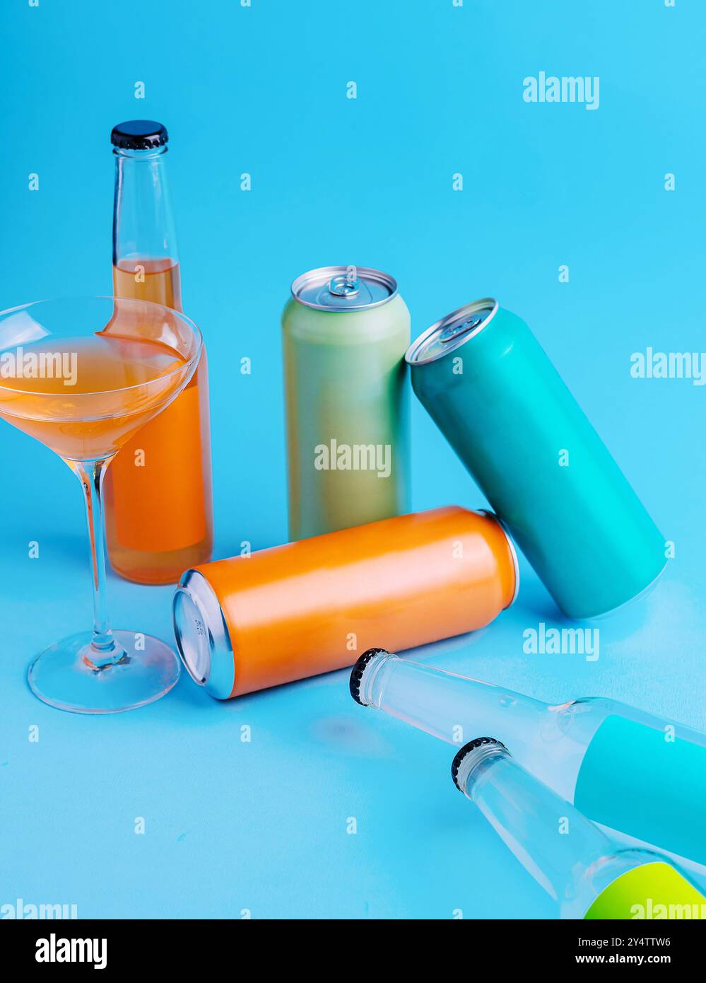 Colorful aluminum cans and glass bottles with drinks lying on a blue ...