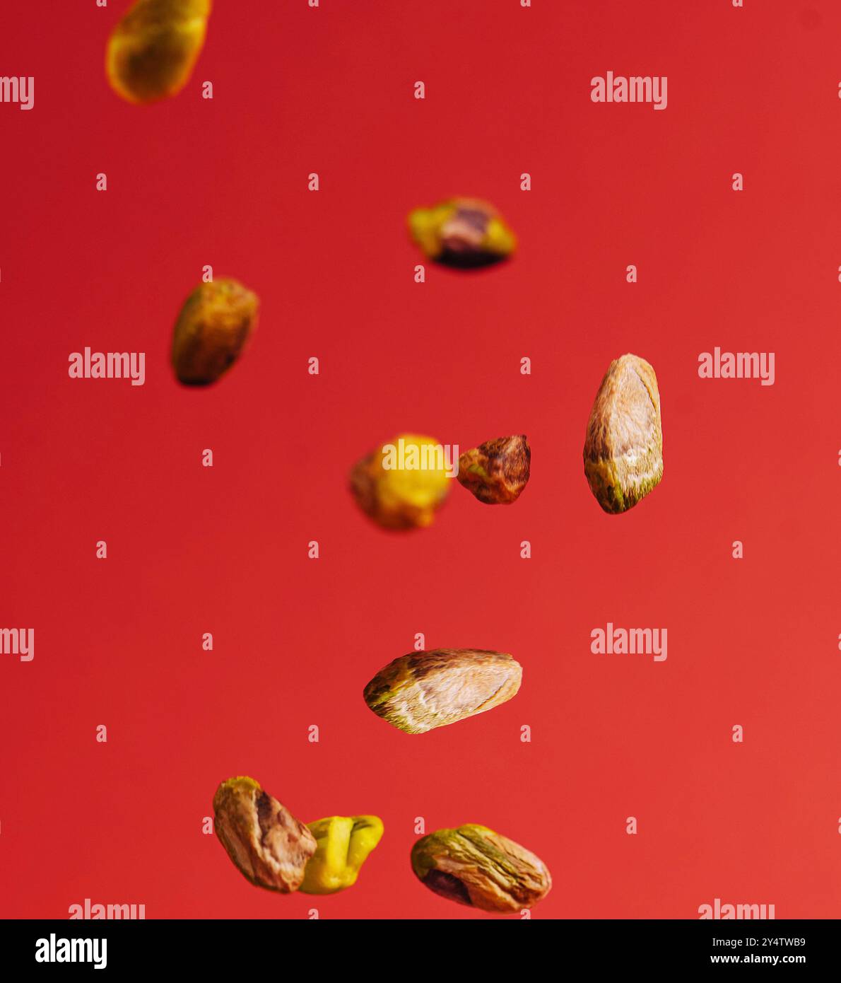 Pistachios with opened shells falling down on a red background Stock ...
