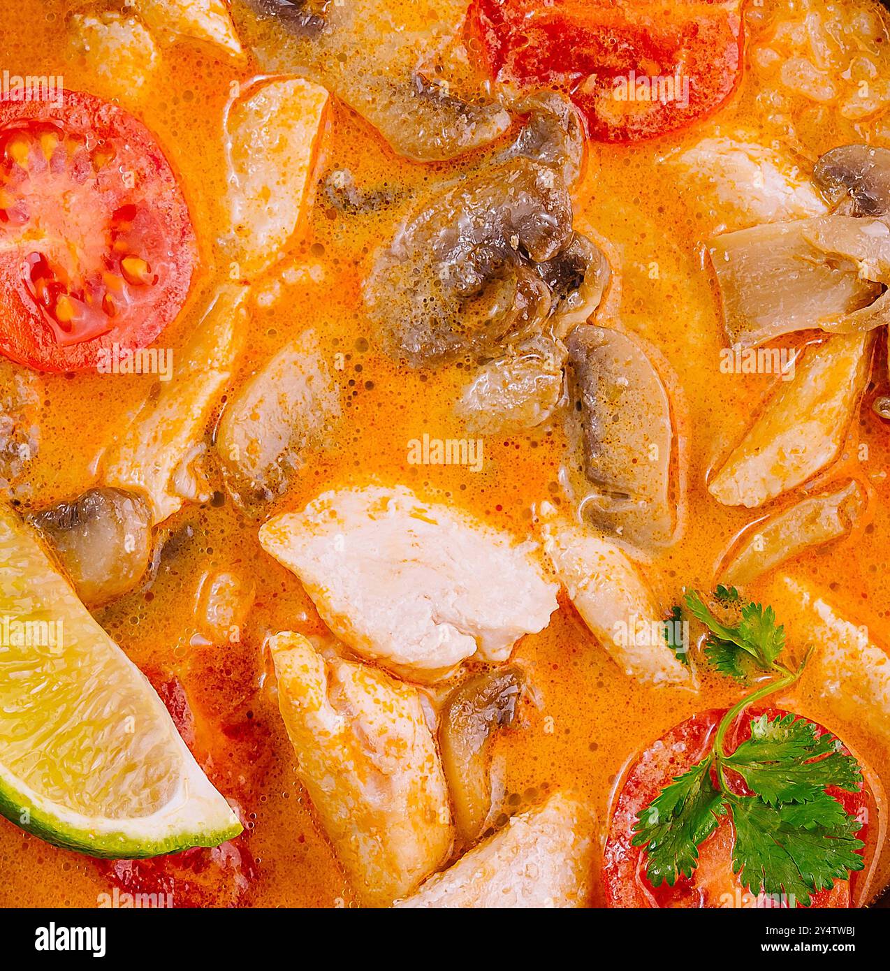 Spicy thai tom yum soup with chicken meat and mushrooms is decorated ...