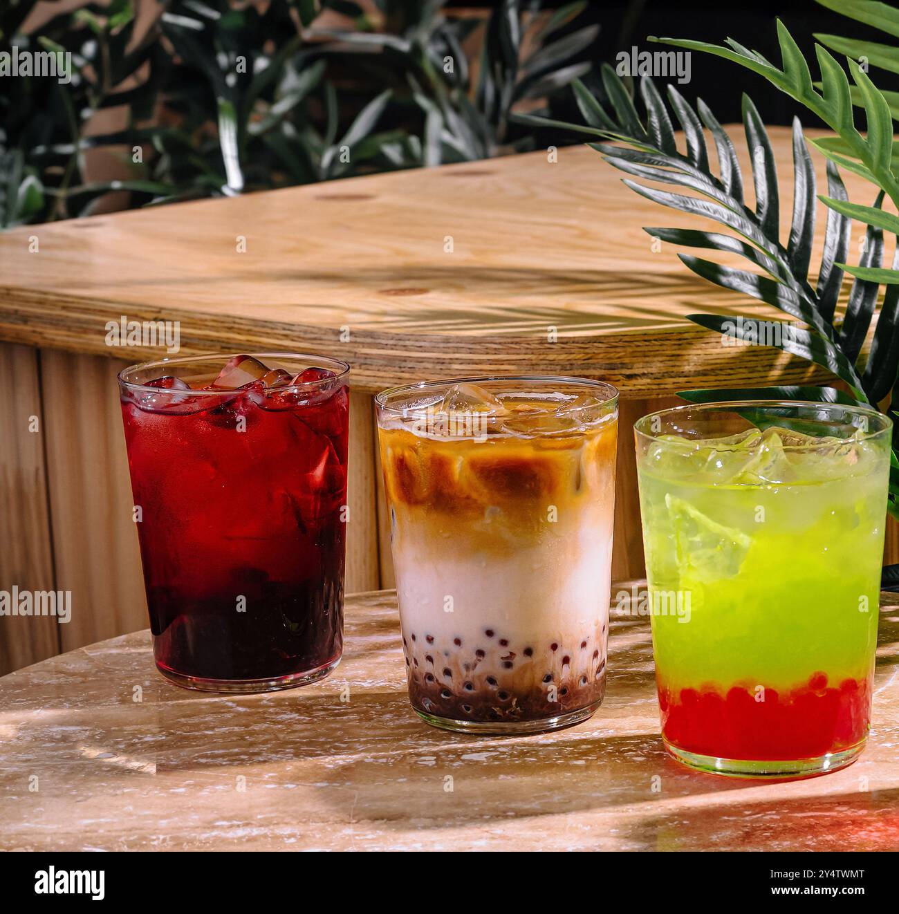 Three colorful bubble tea drinks with ice are sitting on a marble table ...