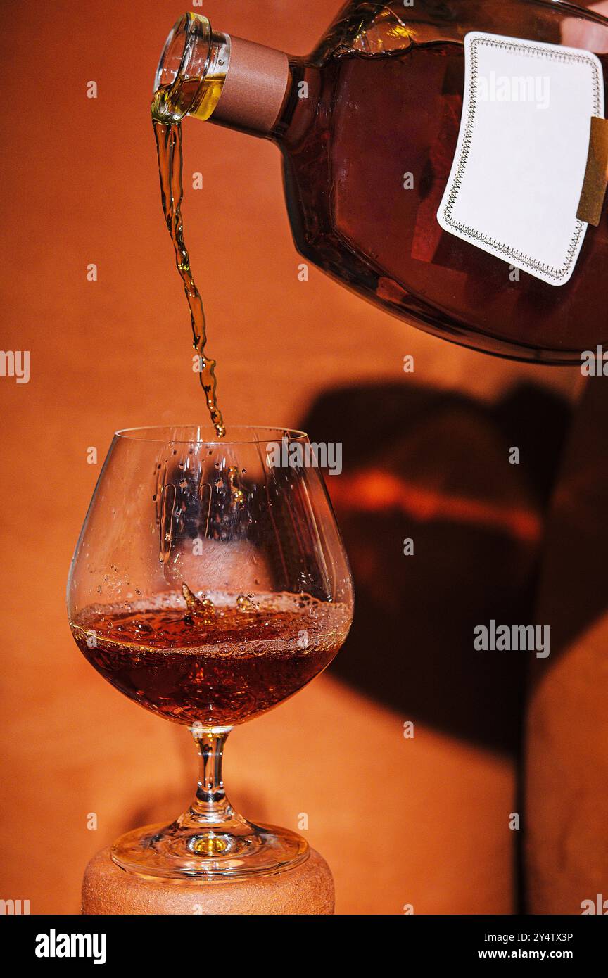 Bartender is pouring brandy from a bottle with a blank label into a ...