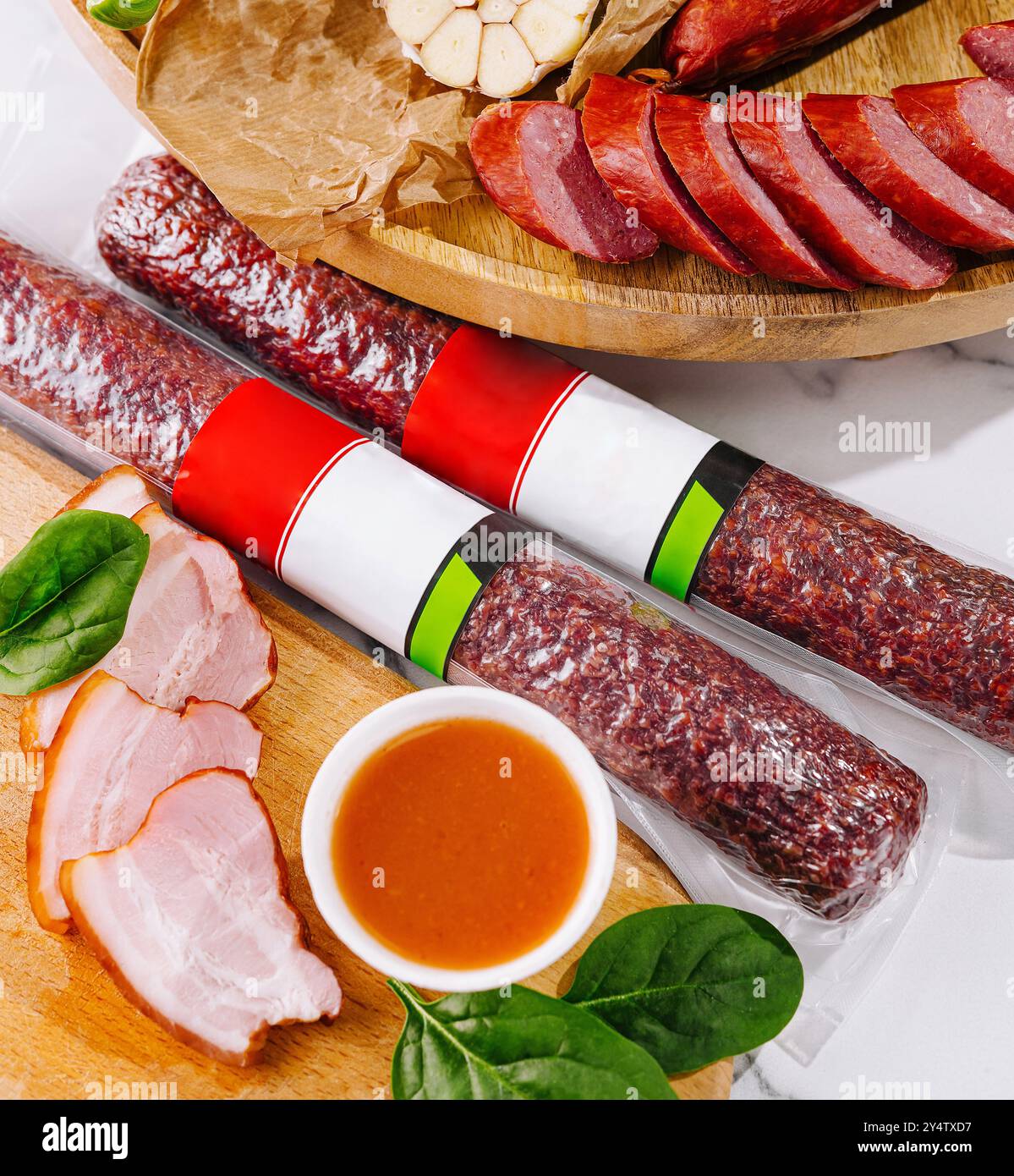 Composition on white marble table of two vacuum packed sausages lying ...