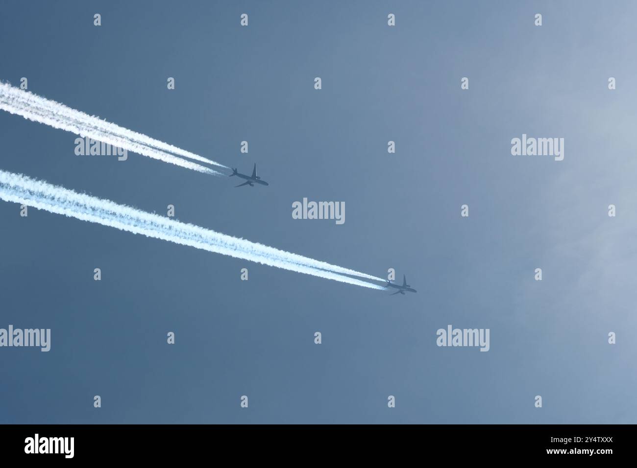 Two planes are flying towards the sun. Airplanes in the blue sky ...