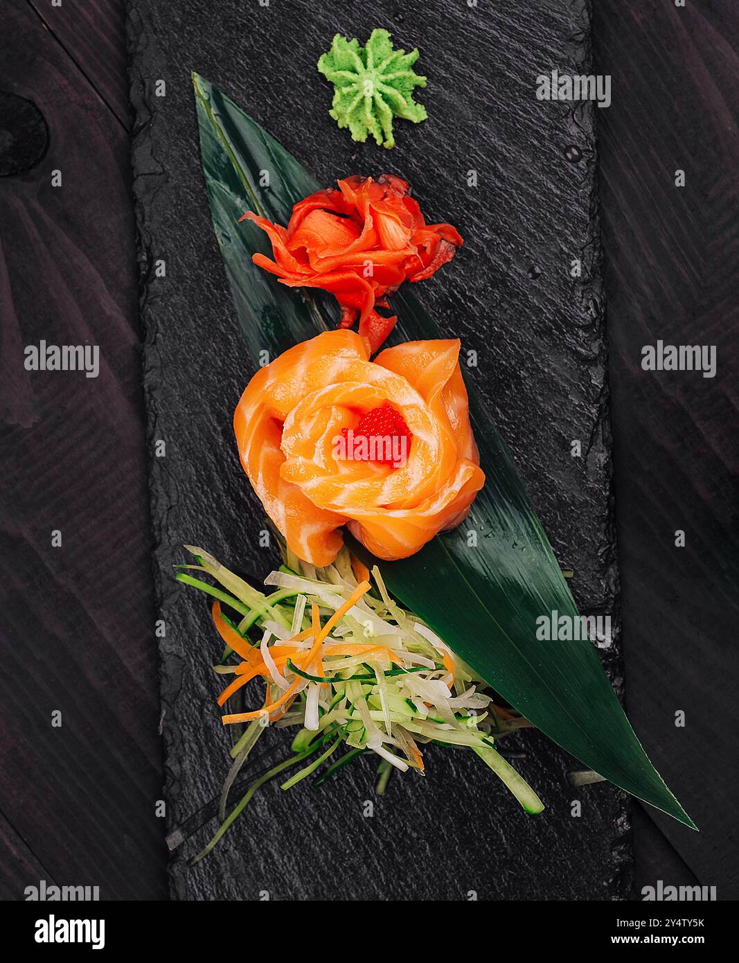 Delicious salmon sashimi appetizer served on black slate with wasabi ...