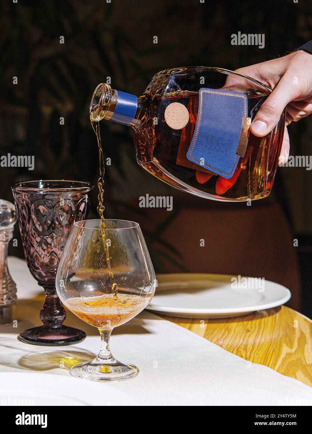Waiter is pouring liquor from a bottle into a glass at a restaurant ...