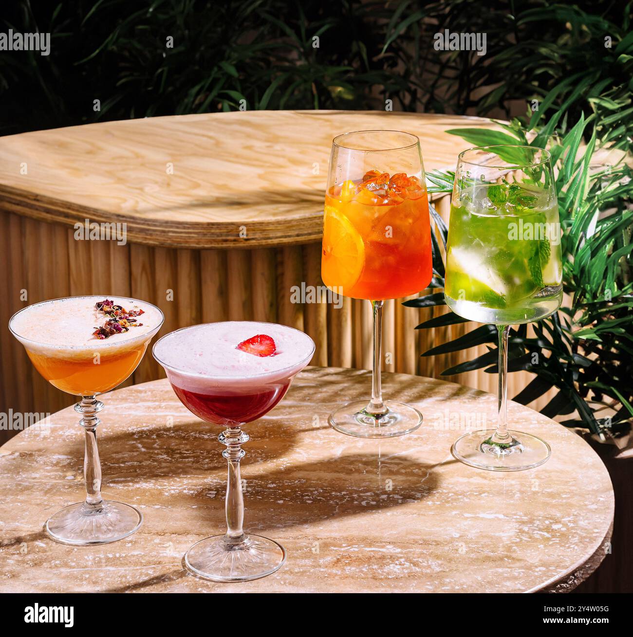Four cocktails with various garnishes are sitting on a table hi-res ...