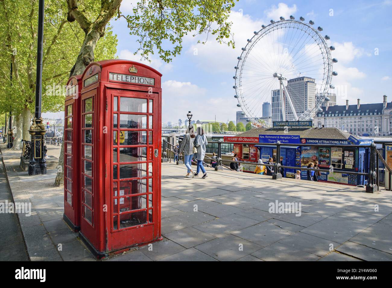 Red telephone box at the north bank of the River Thames with London Eye ...