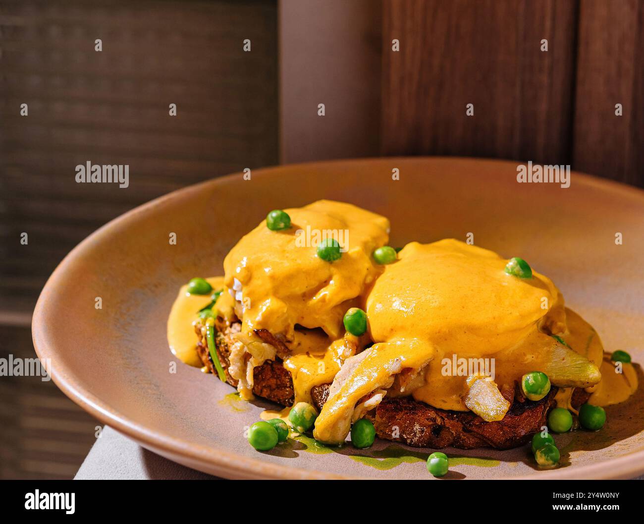 Two toasted buns topped with meat, poached benedict eggs and ...