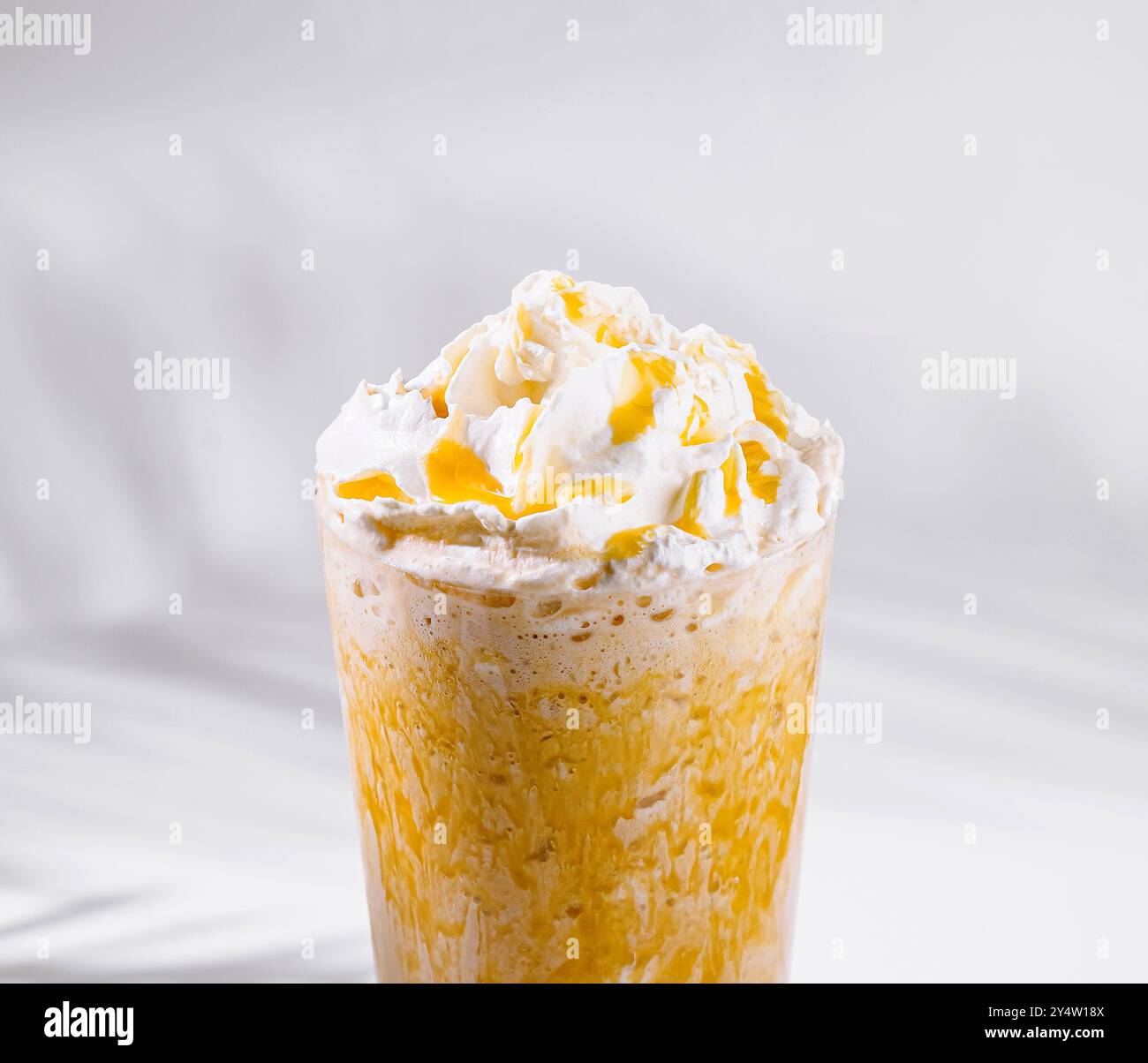 Iced coffee frappe with whipped cream and caramel drizzle on white ...