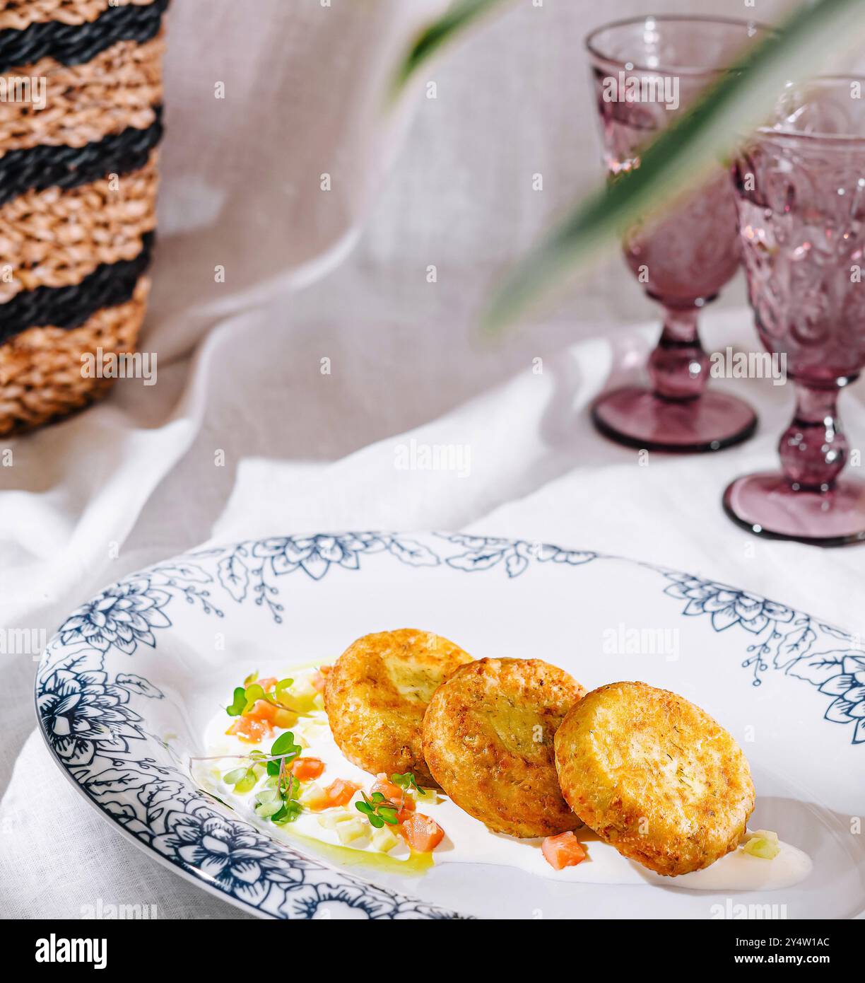 Round potato pancakes served on white plate with floral pattern, white ...