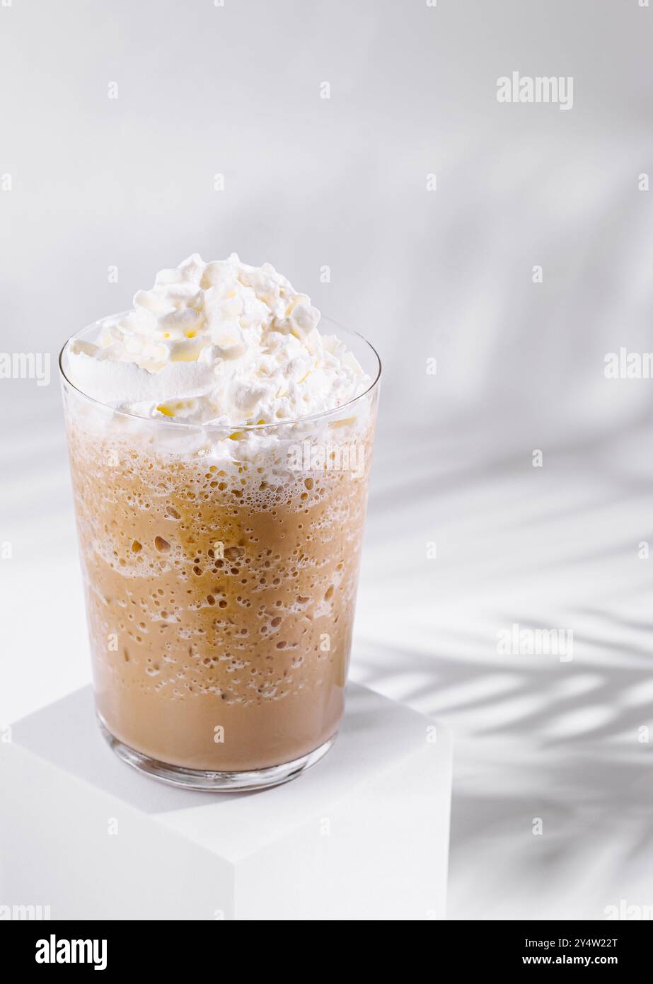 Creamy iced coffee beverage topped with whipped cream, sitting on white ...