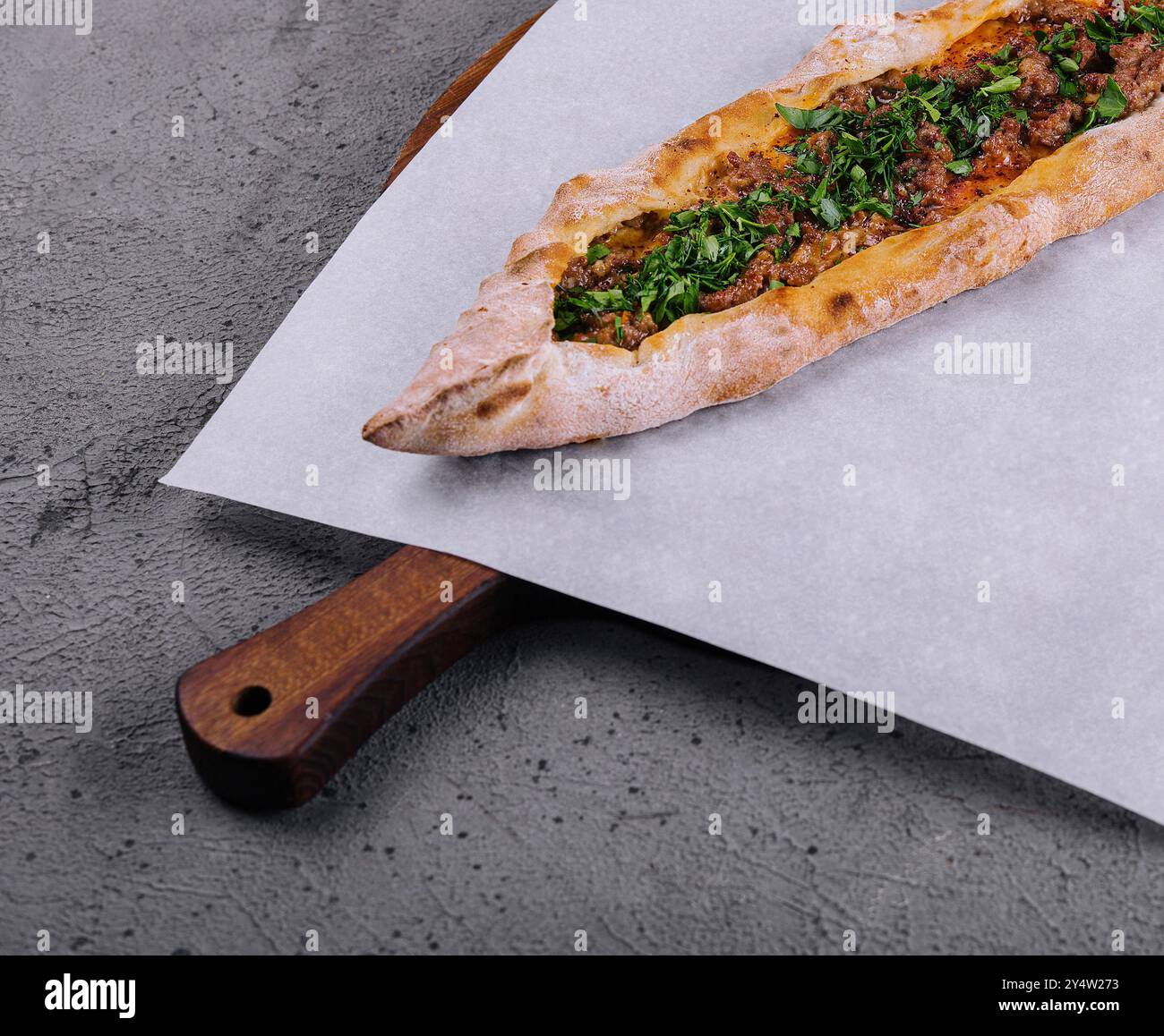 Traditional turkish pide with minced meat and herbs on parchment paper ...