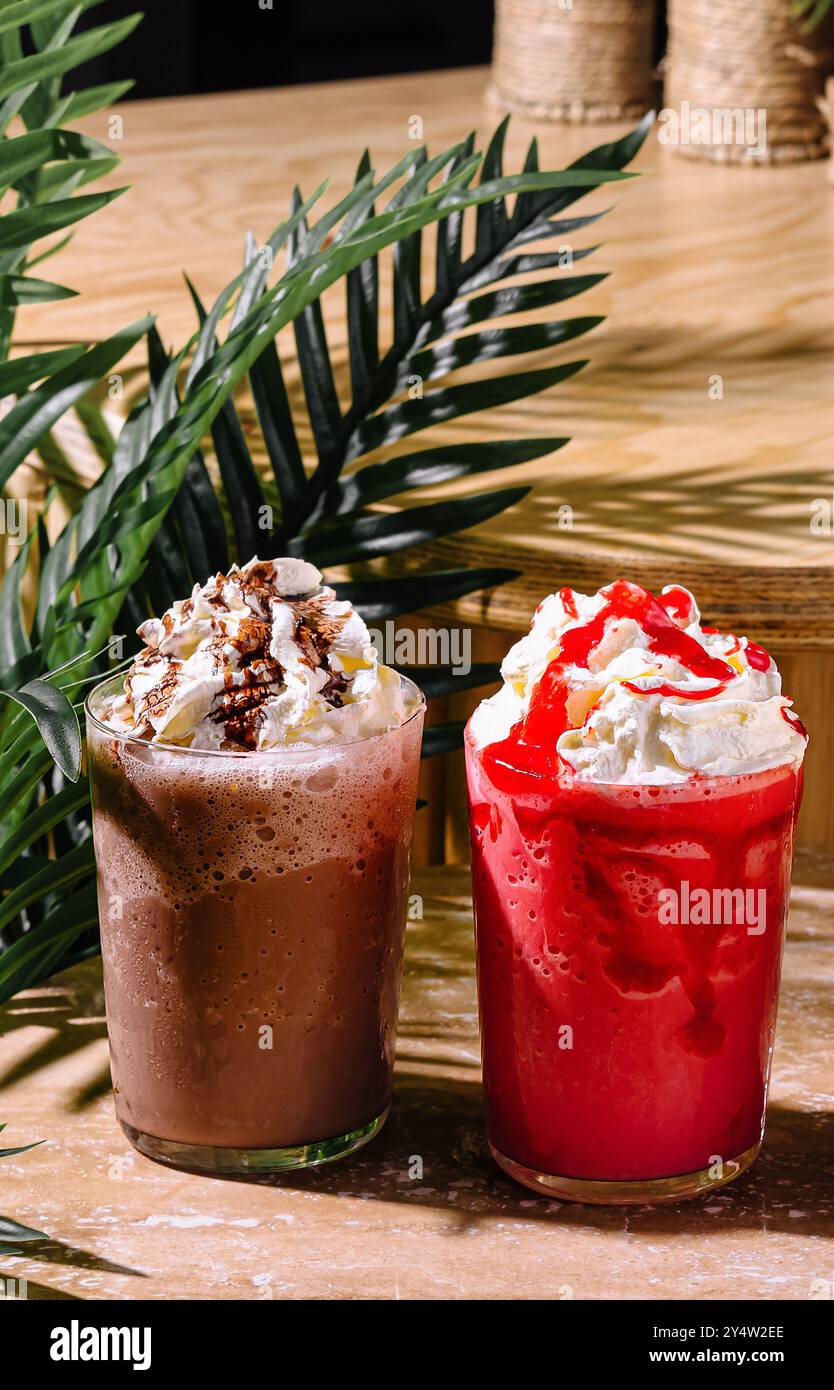 Two milkshakes, chocolate and strawberry flavor, are standing on the ...