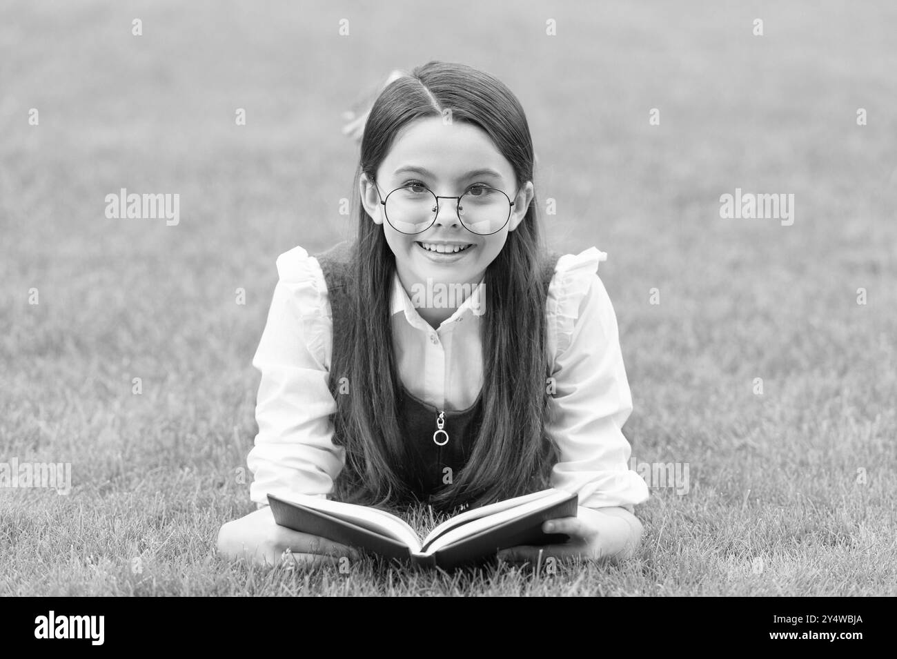 Reading time. Portrait of happy teenage girl reading book lying on ...