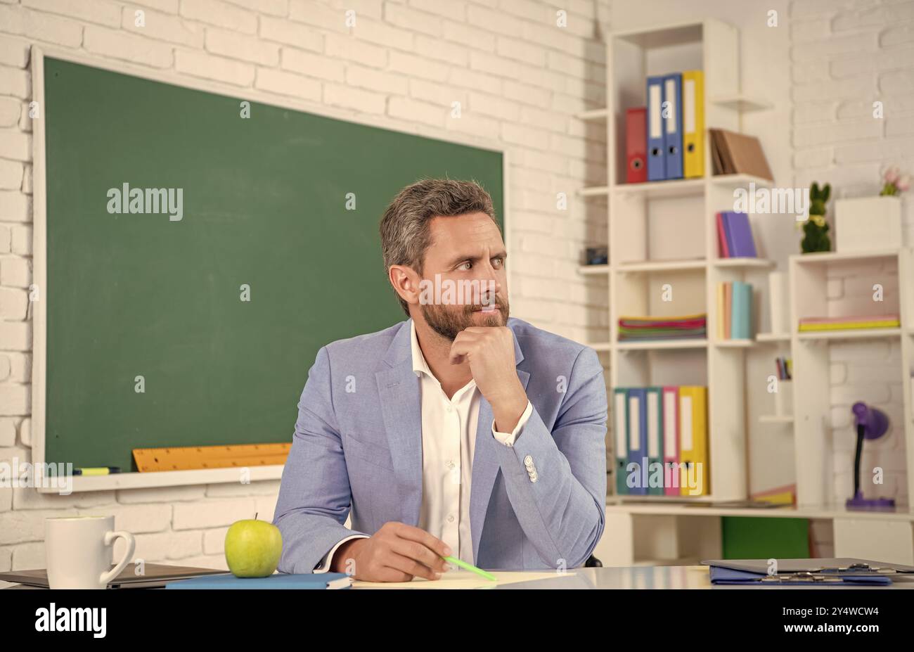 pondering school teacher in classroom at blackboard Stock Photo - Alamy