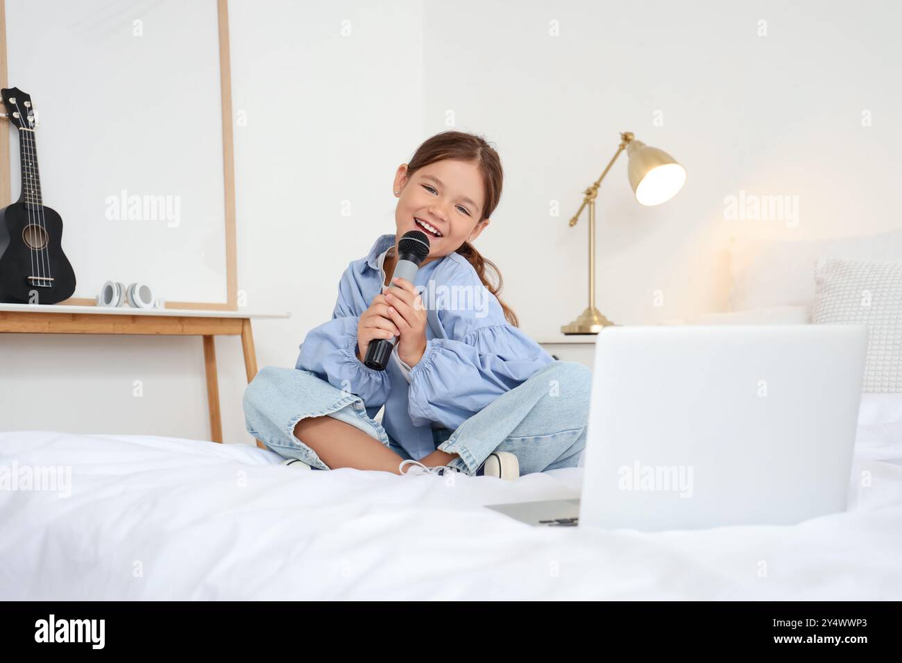 Little girl with microphone and laptop singing in bedroom Stock Photo ...
