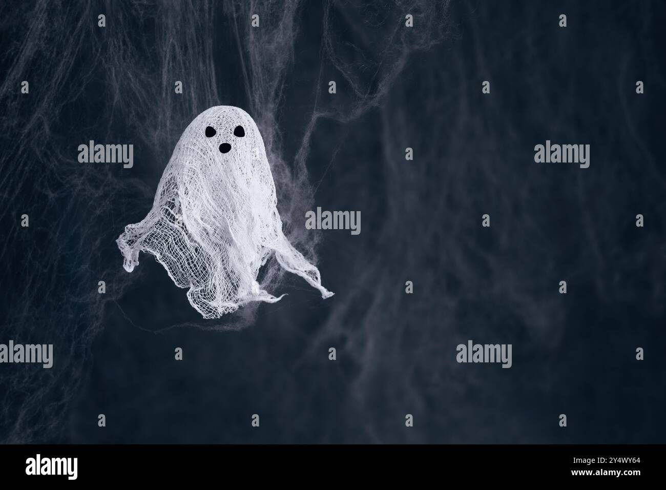 Funny ghost made of gauze and starch on dark spider web background with ...