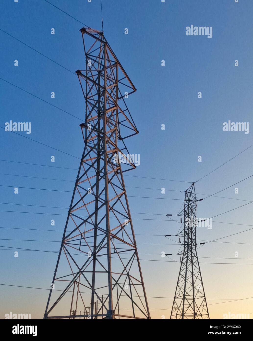 High-tension electrical transmission towers stand against the sunrise ...