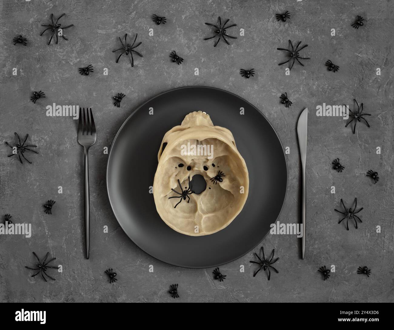 Halloween table setting with black dishes and skull on a dark gray ...