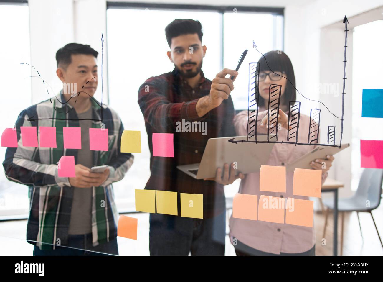 Team collaborating on business strategy with charts and sticky notes ...