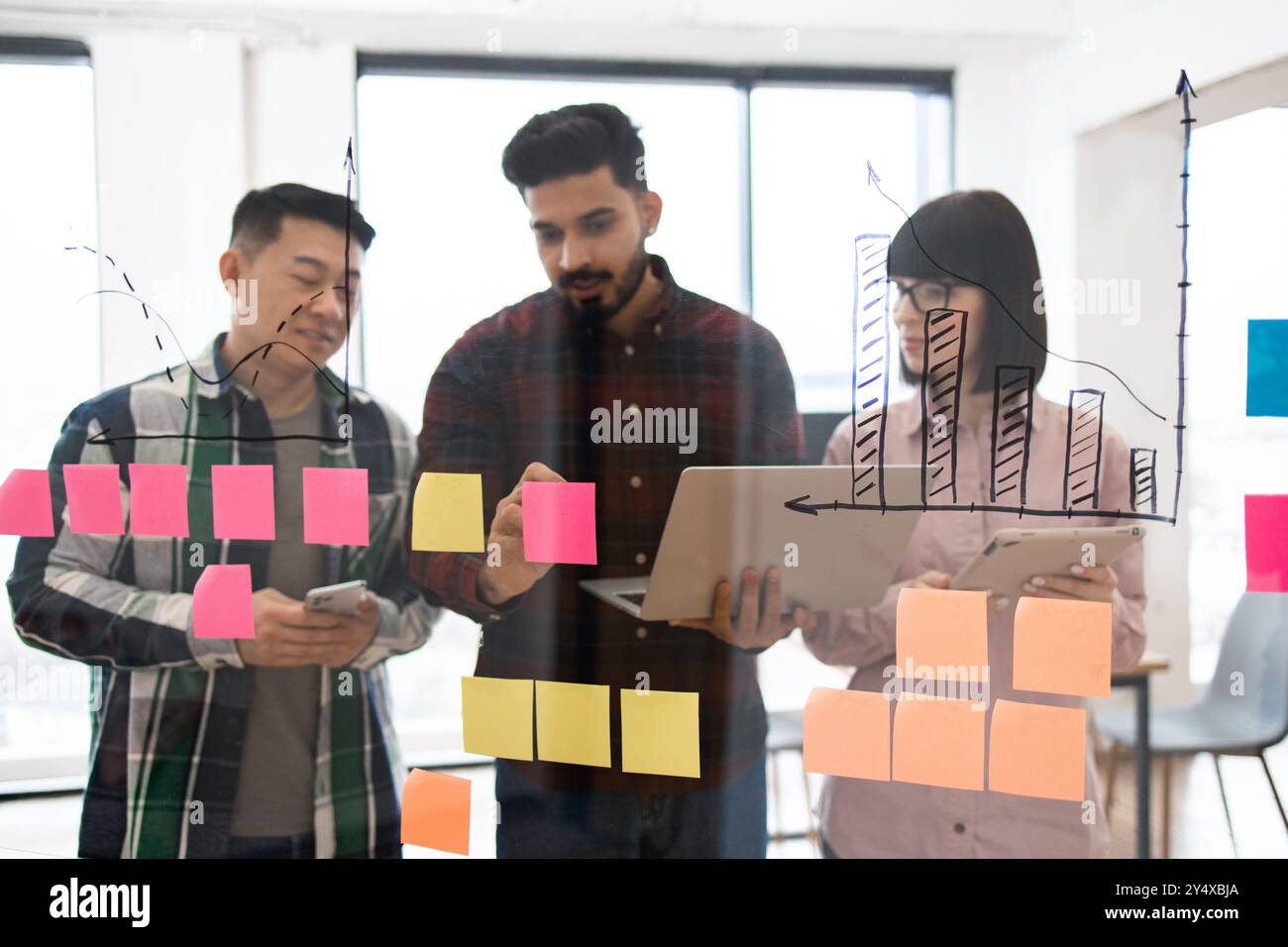 Diverse team brainstorming with sticky notes and graphs in office Stock ...